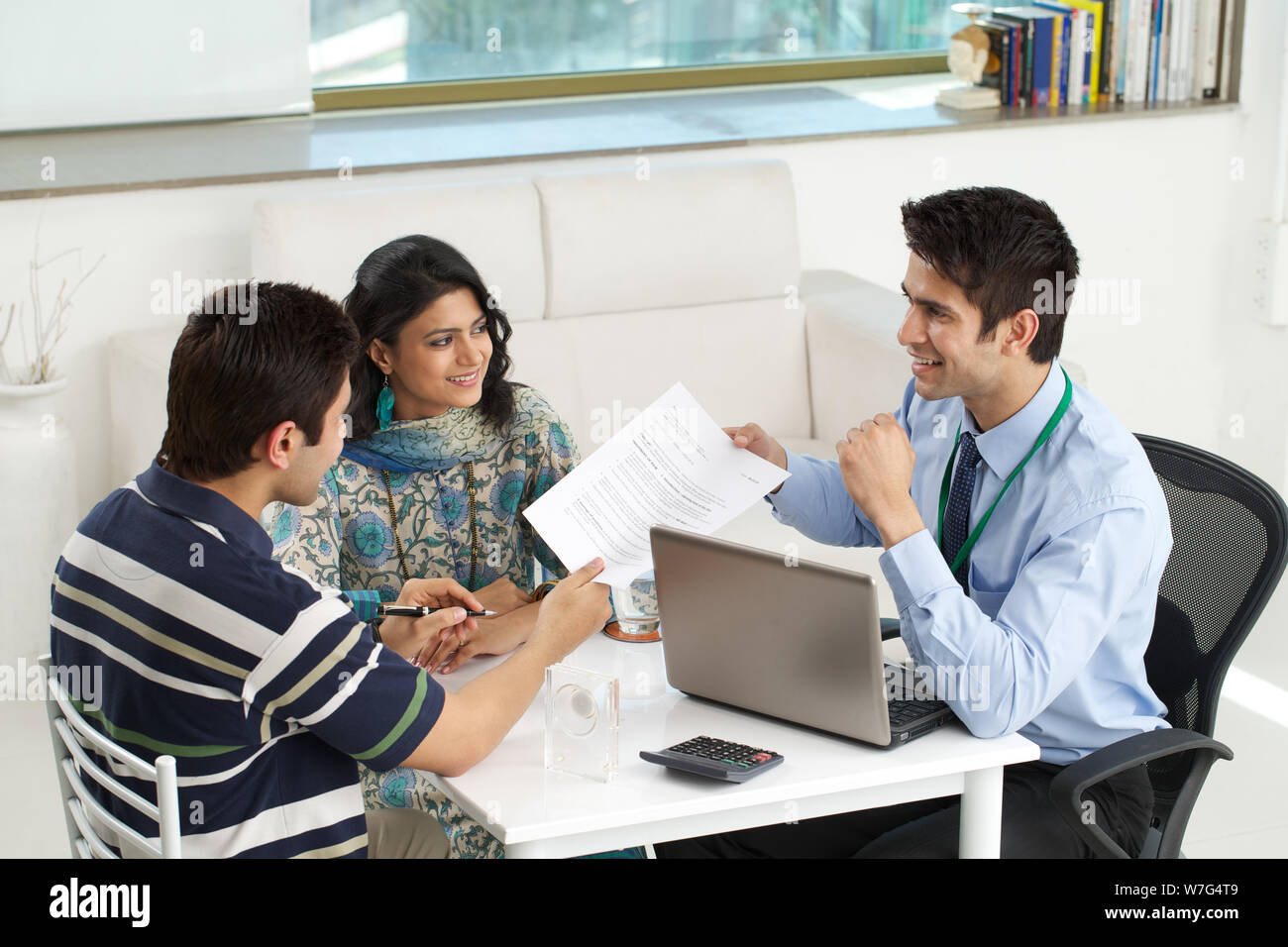 Executive explaining document to a couple Stock Photo - Alamy