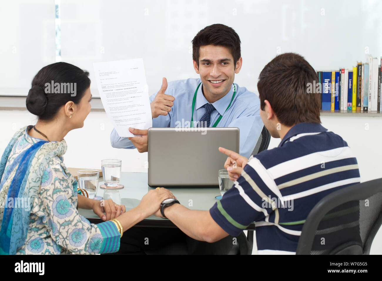 Executive explaining document to a couple showing thumbs up sign Stock ...