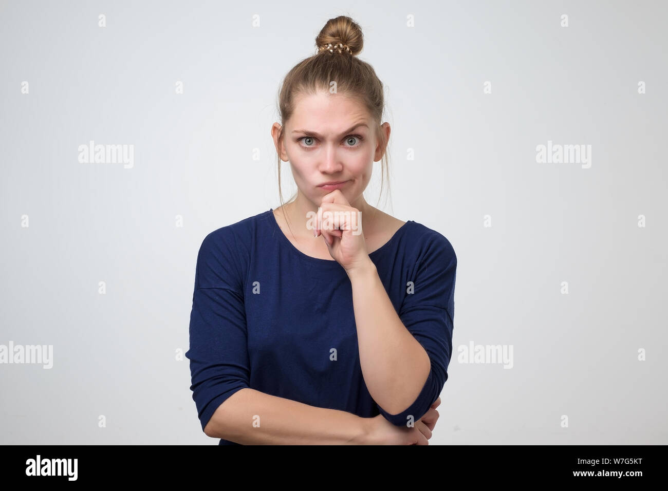 Young serious angry woman with hair bun looking suspicious at camera ...