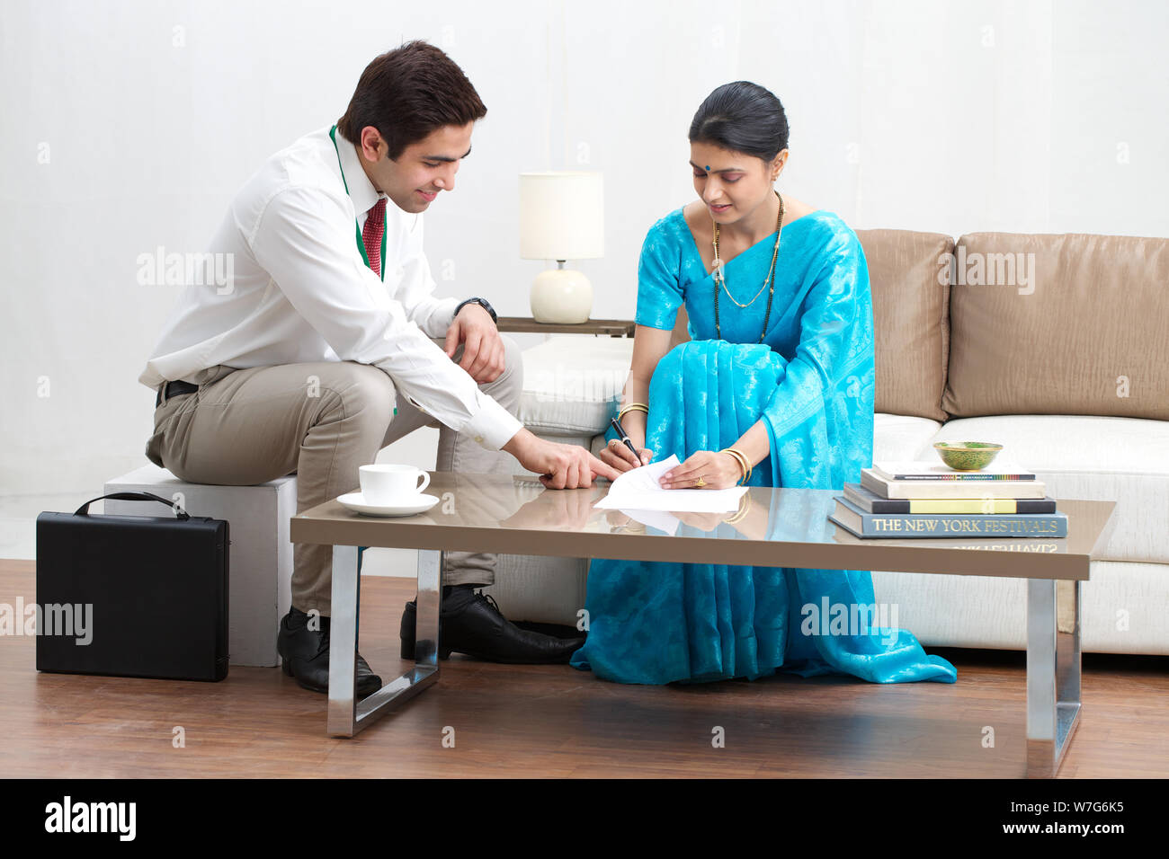 Young woman signing documents with financial advisor Stock Photo - Alamy