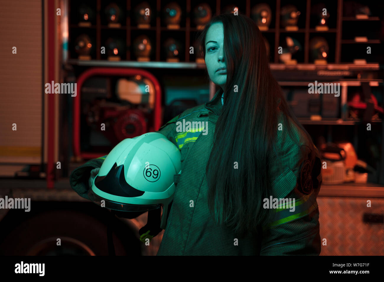 Image of female firefighter with long hair with helmet in her hands at ...