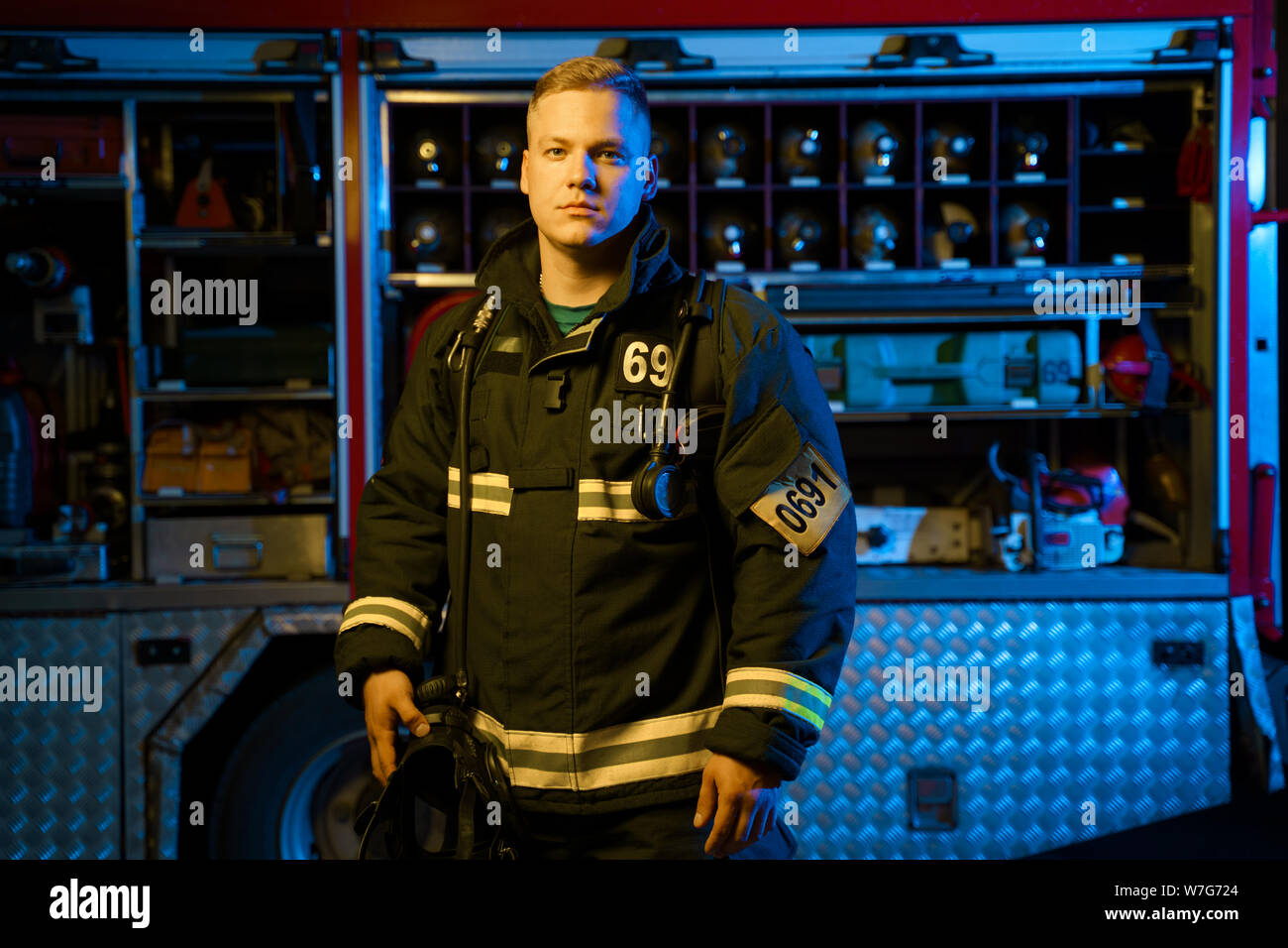 Image of firefighter with helmet in his hand looking into camera while ...