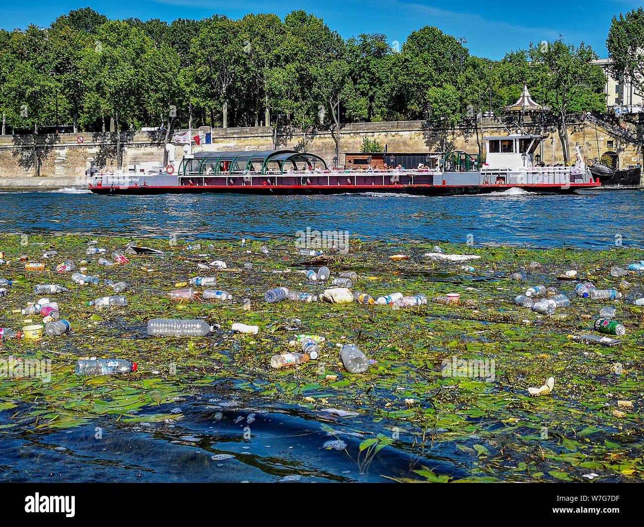 big amount of plastic waste swimming on water surface with water plants ...