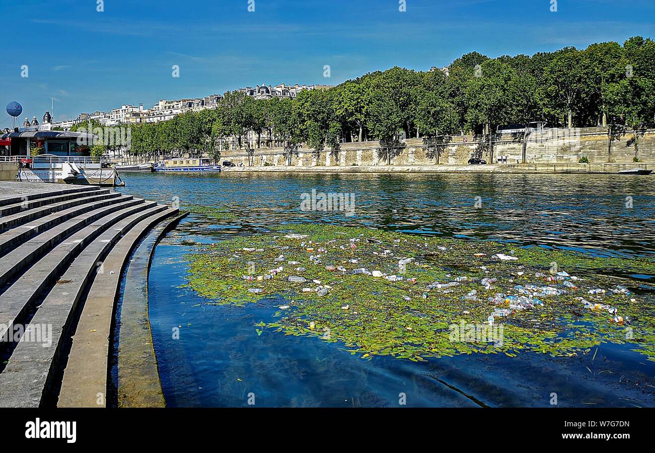 big amount of plastic waste swimming on water surface with water plants ...