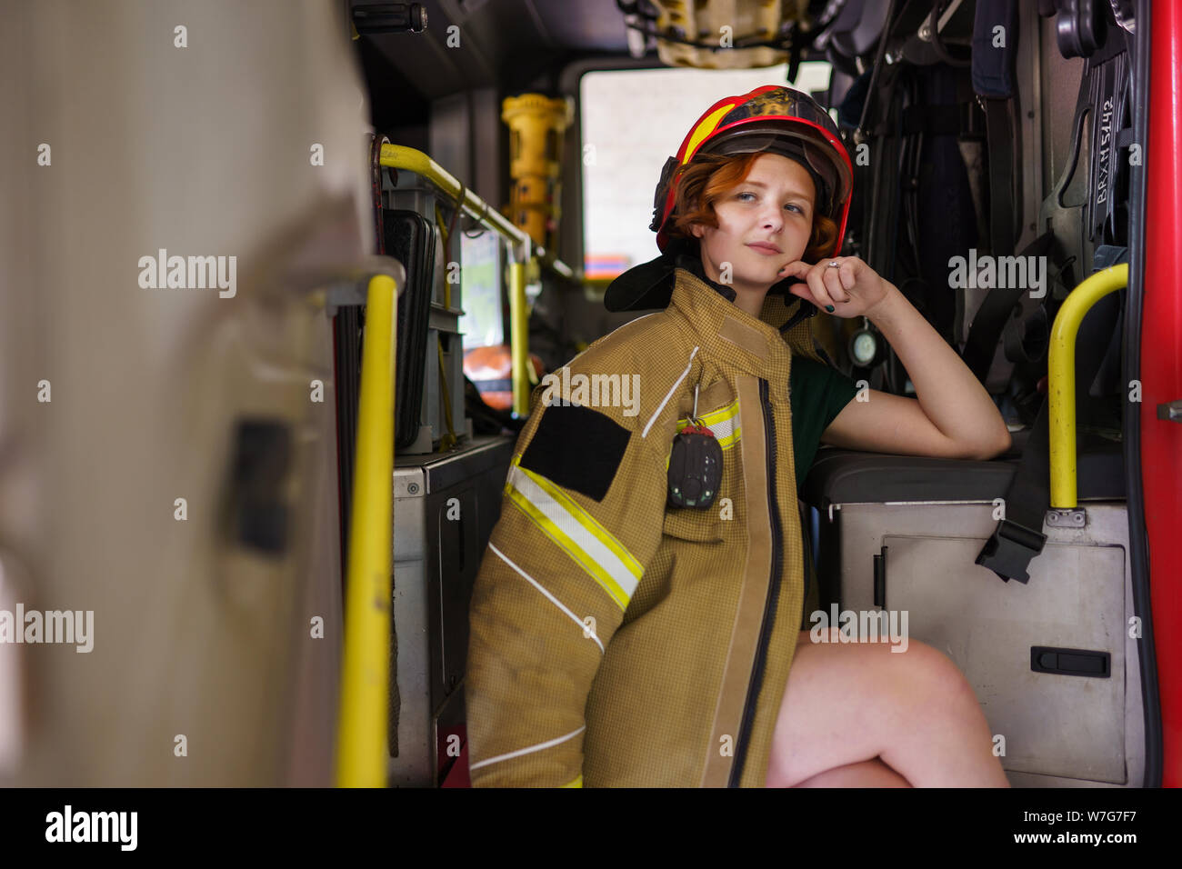 Image of ginger firewoman looking in camera sitting in cab of fire ...