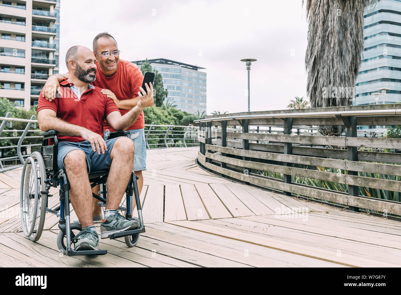 disabled man in wheelchair making a selfie with his phone with a friend ...