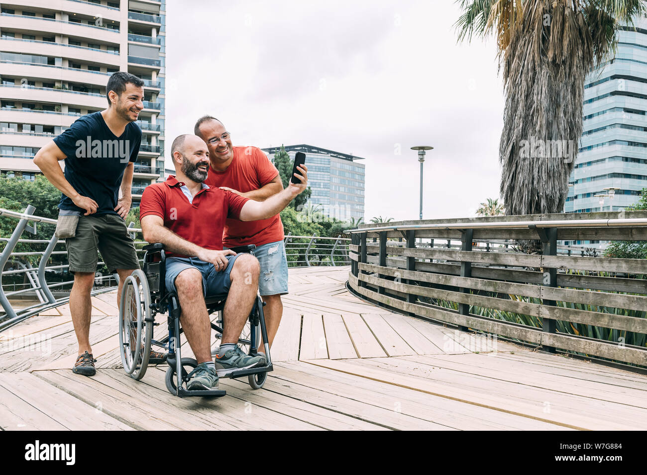 disabled man in wheelchair taking a selfie with his phone with two ...