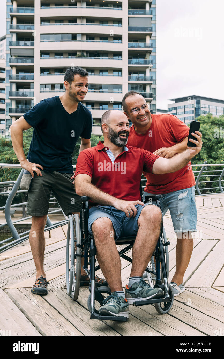disabled man in wheelchair making selfie with his phone with two ...