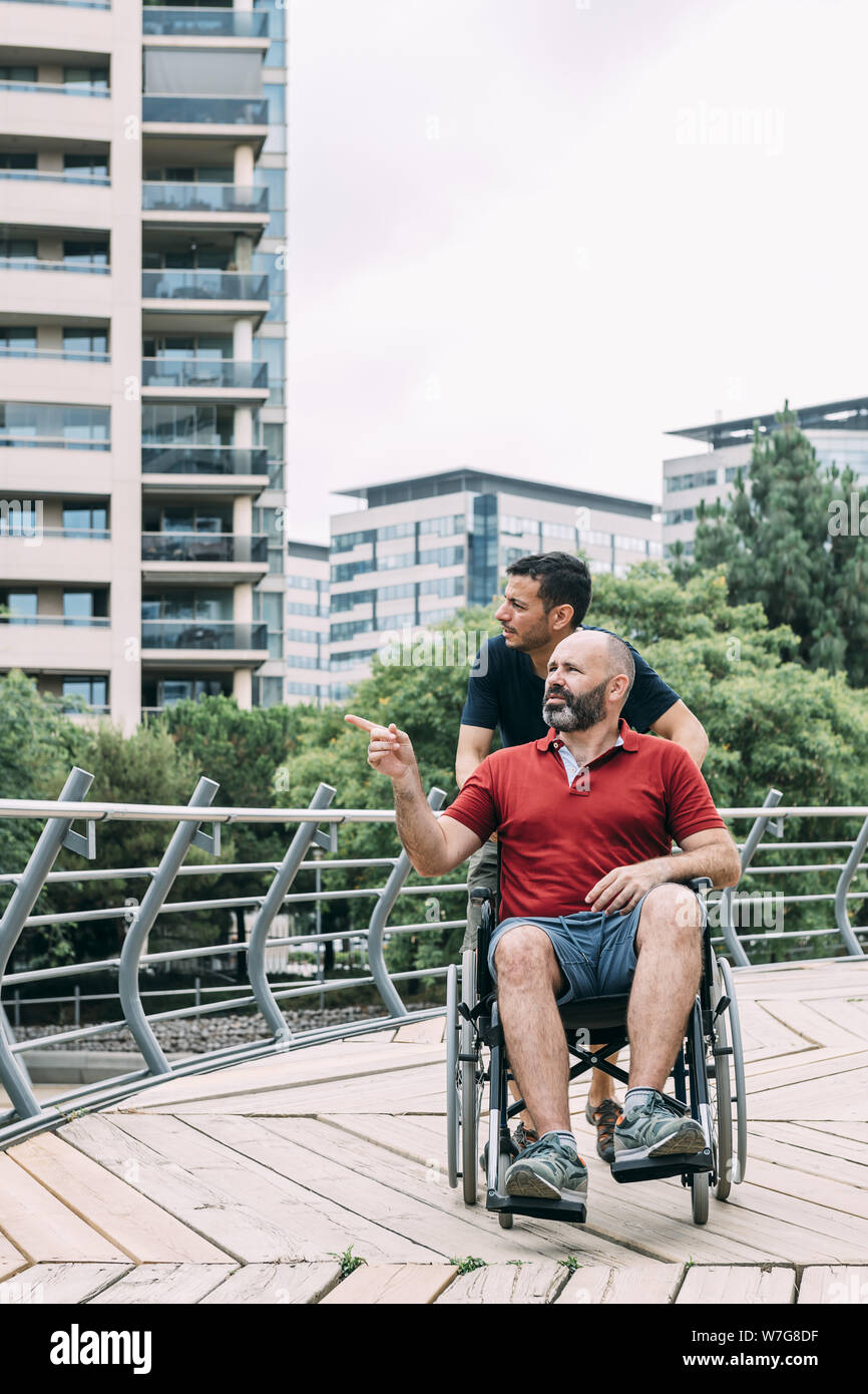 disabled man in wheelchair conversing with his friend during a walk ...