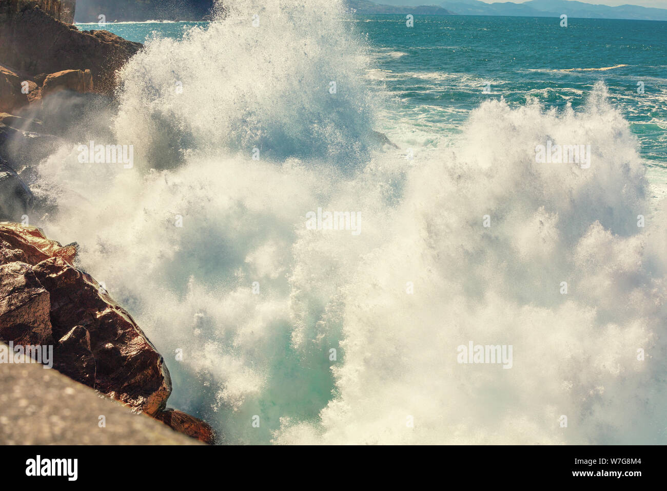 A huge wave is breaking on the rocks. Splash of the wave. Rocky ...