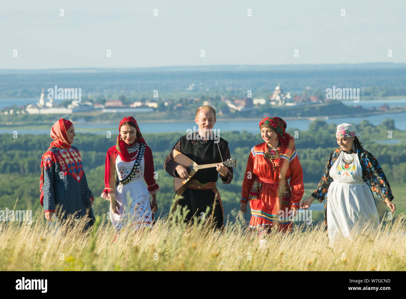 Smiling people in traditional russian clothes walking on the field - a ...