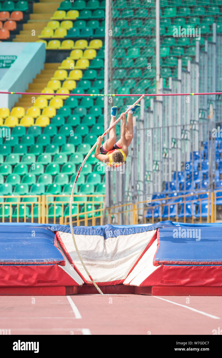 Pole vault - a young woman rest on the pole and ready to jump over the ...