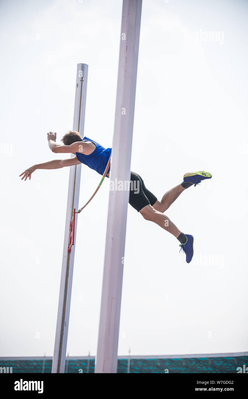 Pole vault - a young athletic man jumping over the bar Stock Photo - Alamy