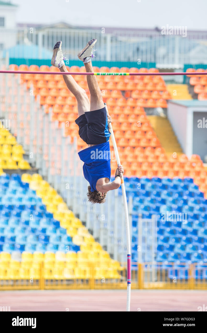 Pole vault - a bearded athletic man rest against the ground on the pole ...