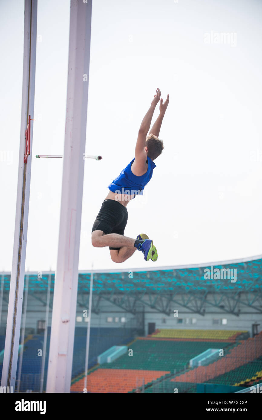 Pole vault - a young athletic man falling down on the mat after jumping ...