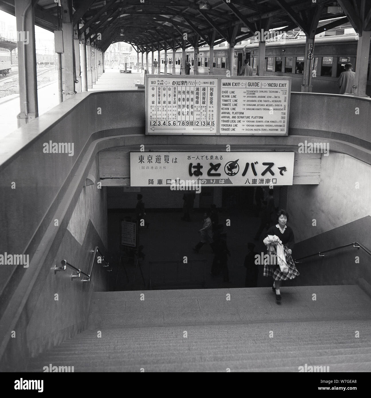 1960s, historical, Tokyo, Japan and a femle commuter going up steps to ...