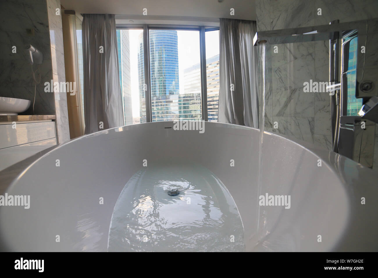 Water filling in modern bathtub in bathroom interior - modern glass ...