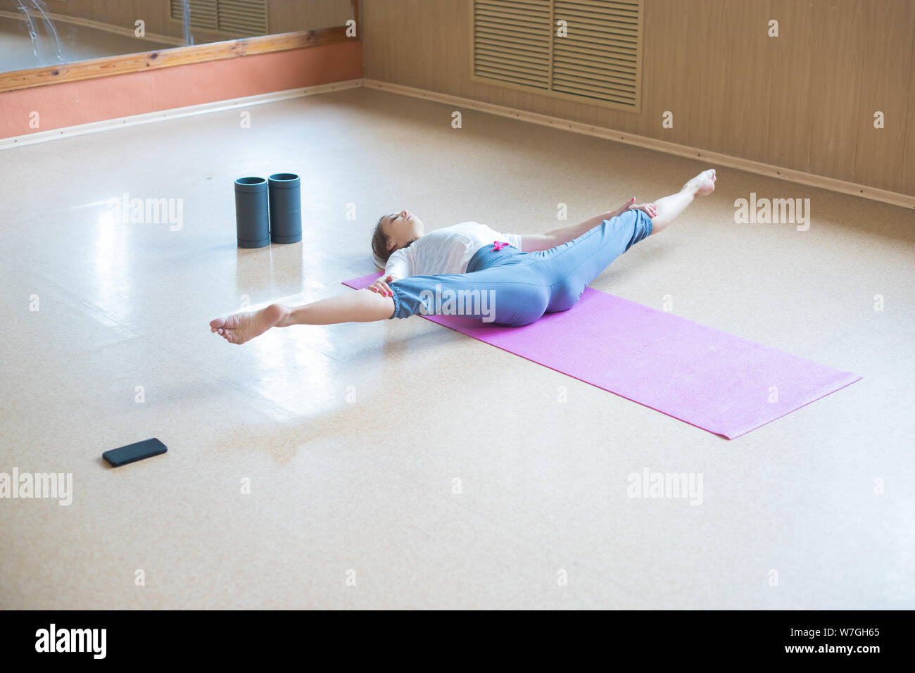 Young woman doing exercises on the yoga mat - performing a split and ...