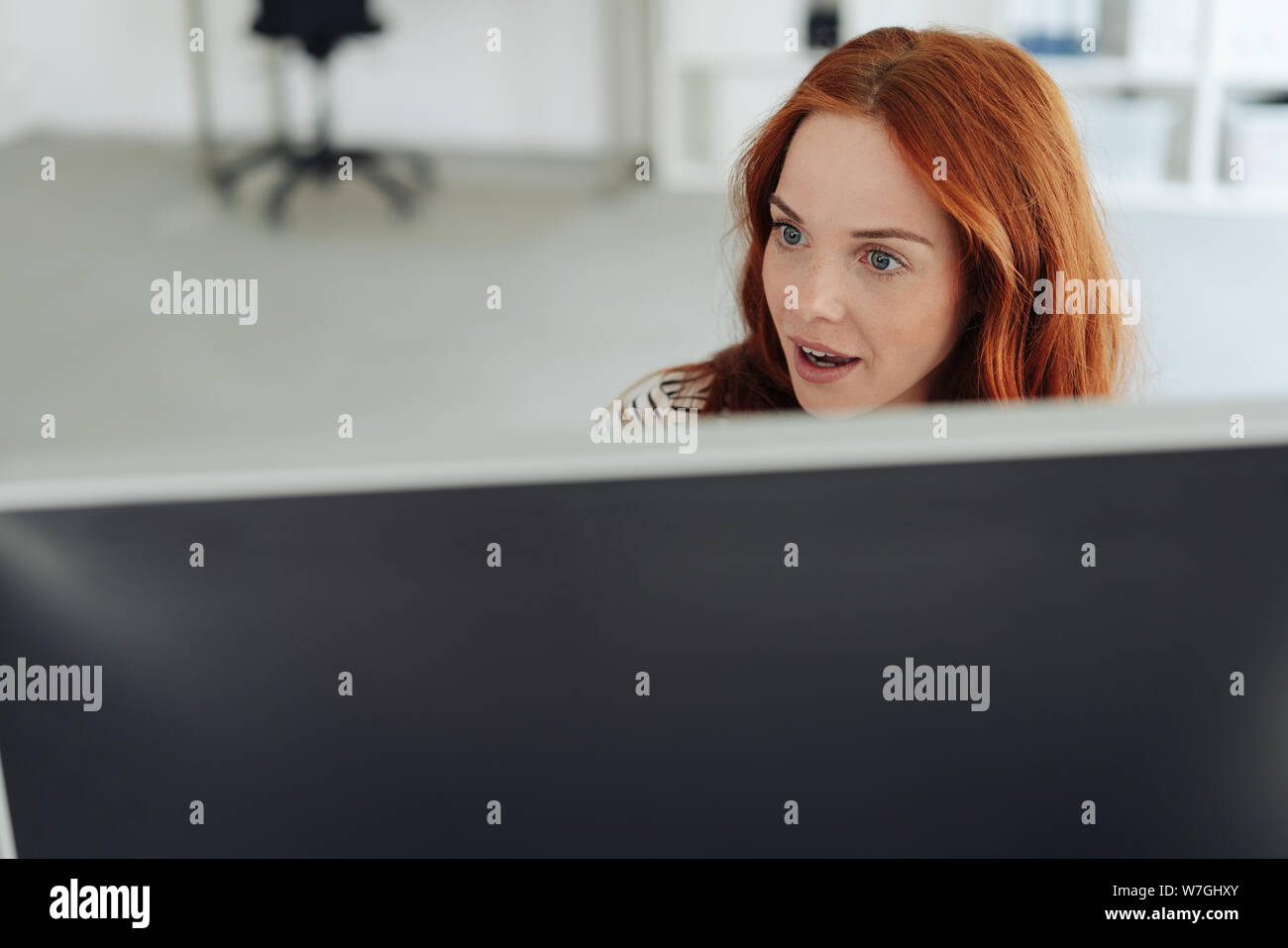 Shocked or surprised young businesswoman gawping at her desktop monitor ...