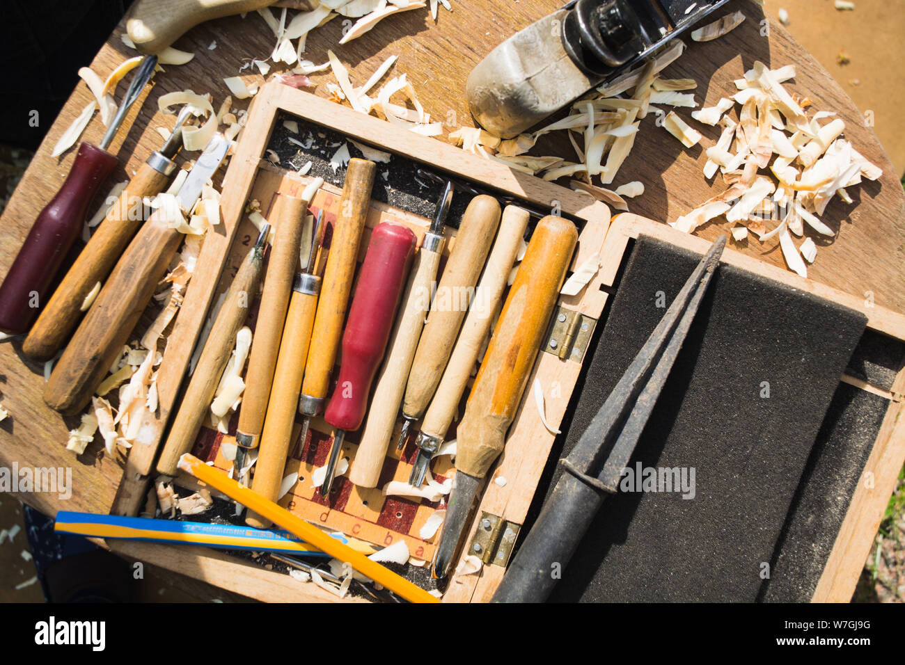 Metal and wooden tools for wood carving in box with shavings. Top view ...