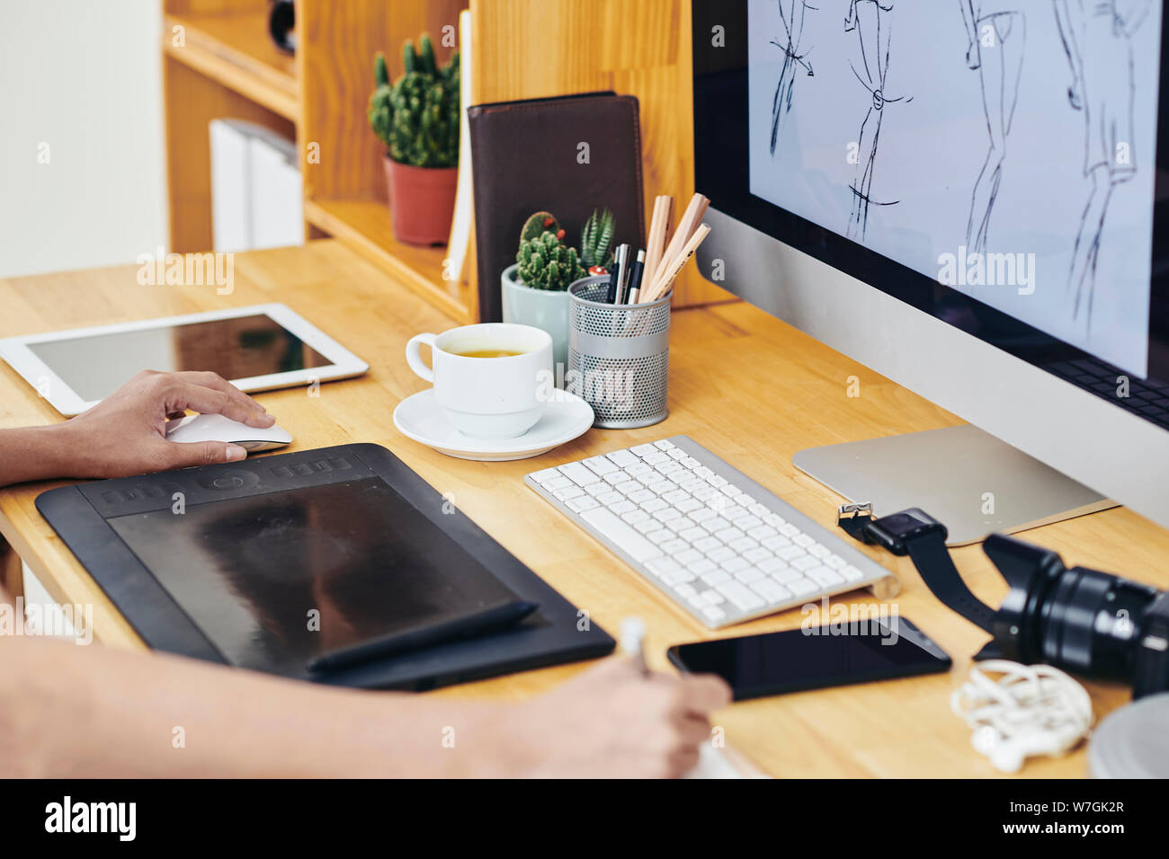 Cropped image of graphic designer working on computer and writing down ...