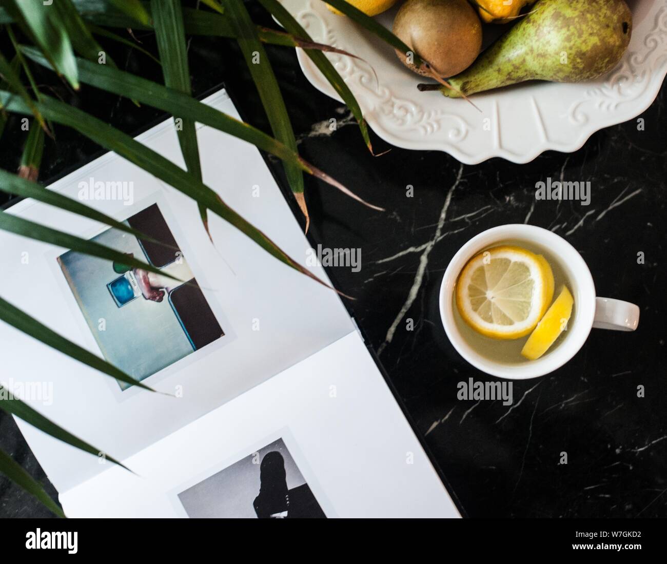 Overhead shot of a lemon tea with an art book on the side and pears ...