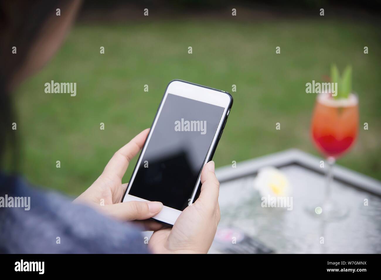 Lady using mobile phone relax in green garden with soft drink ...
