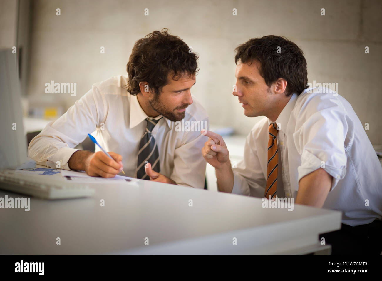 Two businessmen having a discussion at a desk inside an office Stock ...