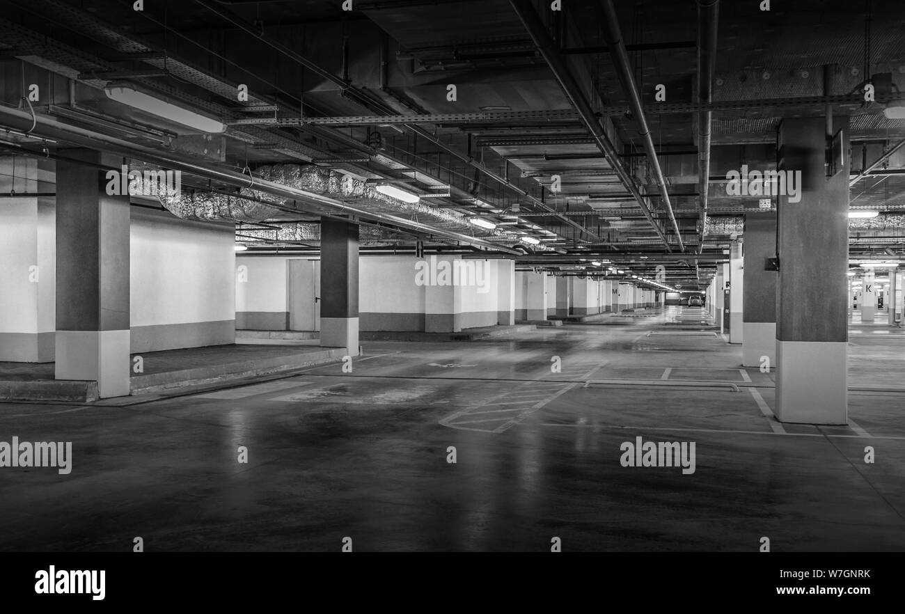 Grungy, dimly lit empty parking garage with overhead lights and an exit ...