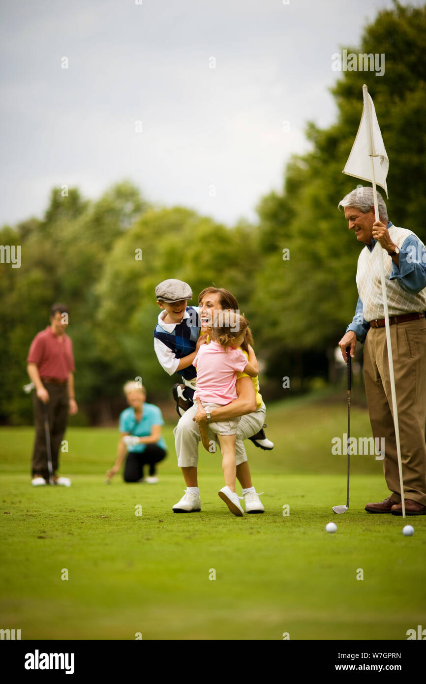 Mother hugging her two young children on a golfing green Stock Photo ...