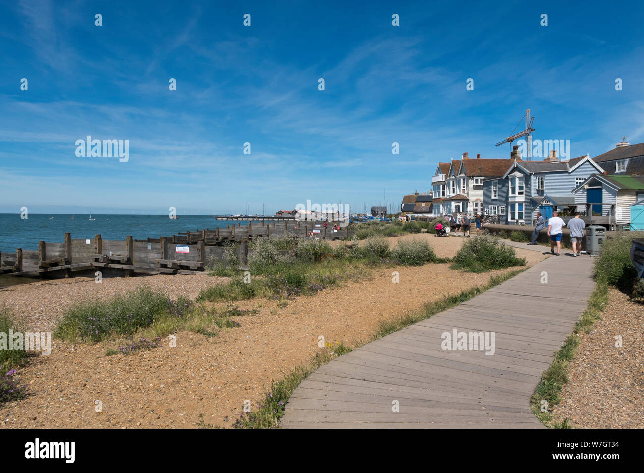 People walking along the boardwalk on the beach at Whitstable, Kent, UK ...