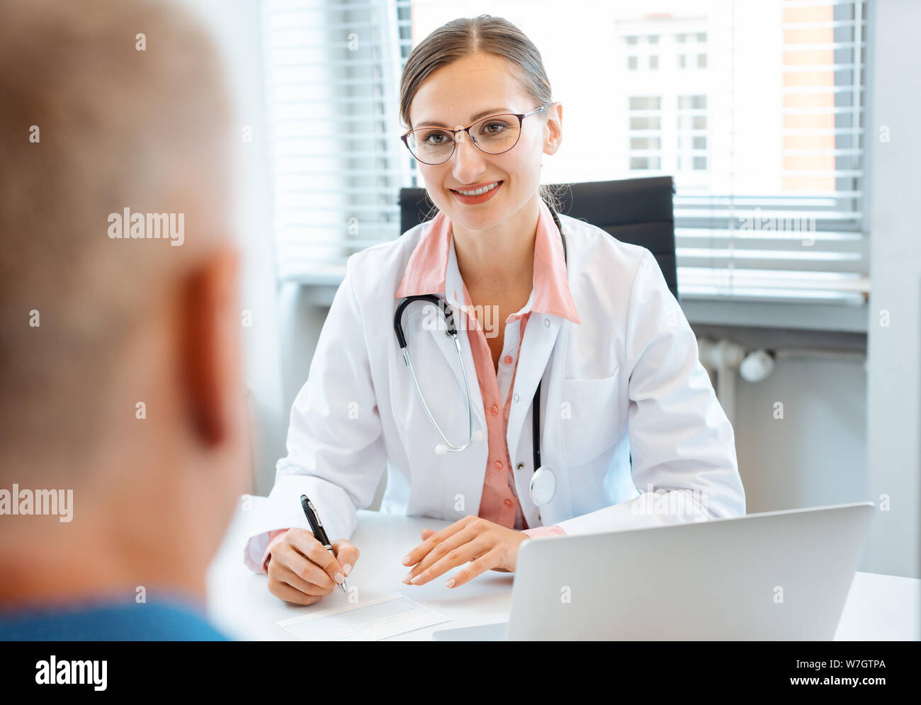 Doctor making notes on report of patient Stock Photo - Alamy