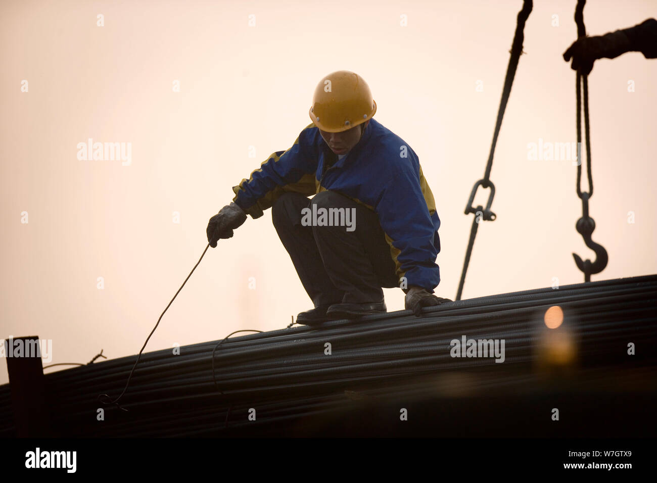 Young adult male construction worker atop steel poles attached to a ...