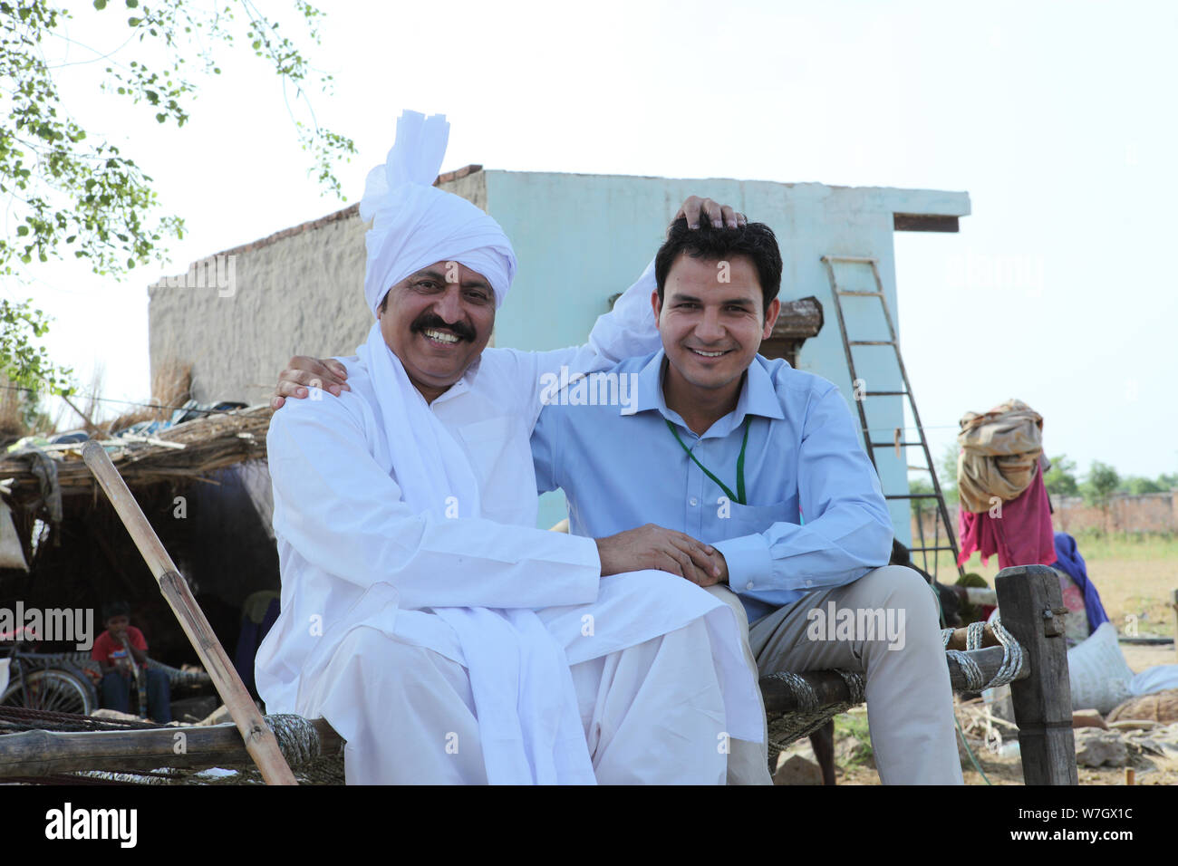 Rural man with his son sitting on cot and smiling Stock Photo - Alamy