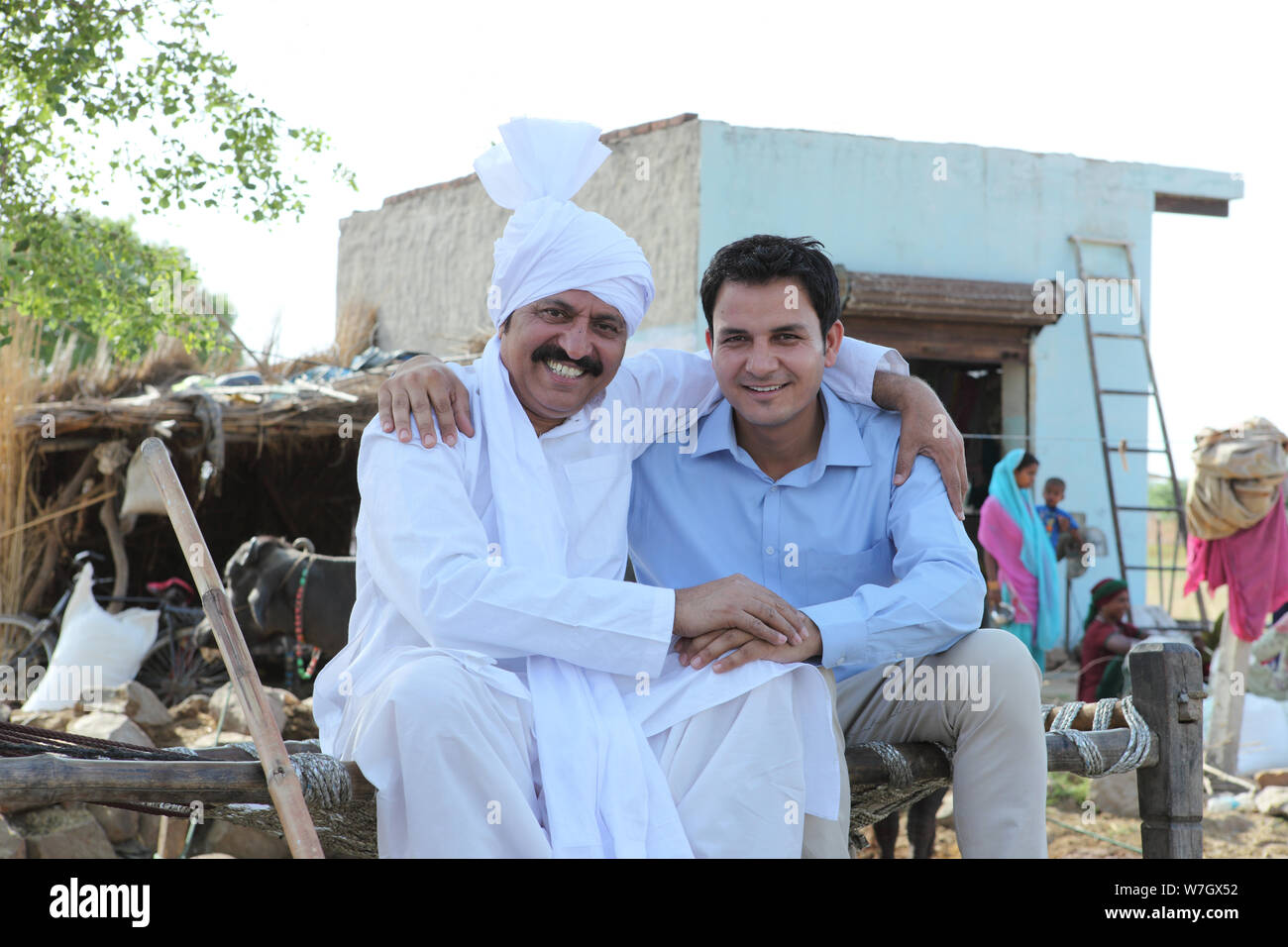Rural man with his son sitting on cot and smiling Stock Photo - Alamy