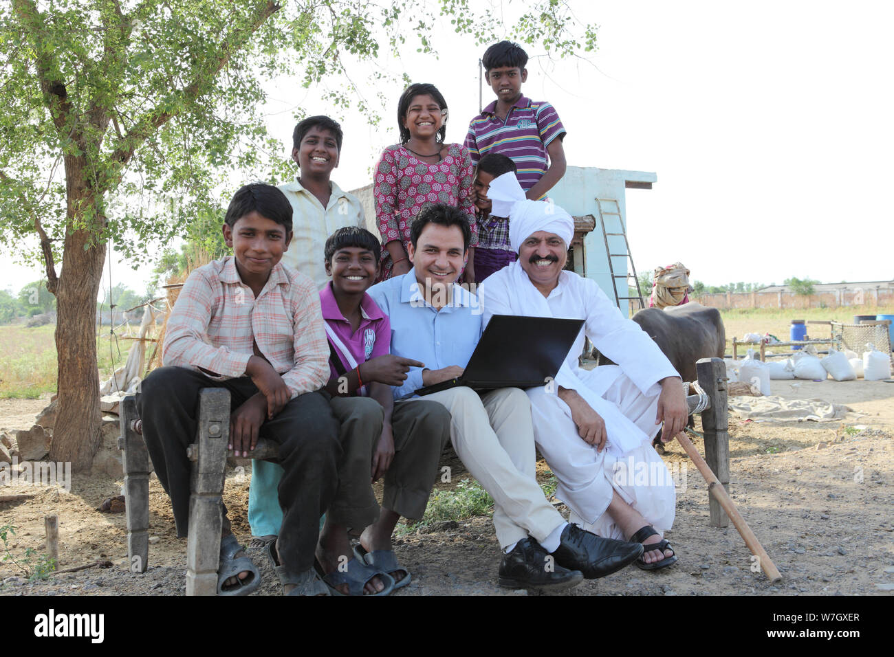 Executive explaining on laptop to rural people Stock Photo - Alamy