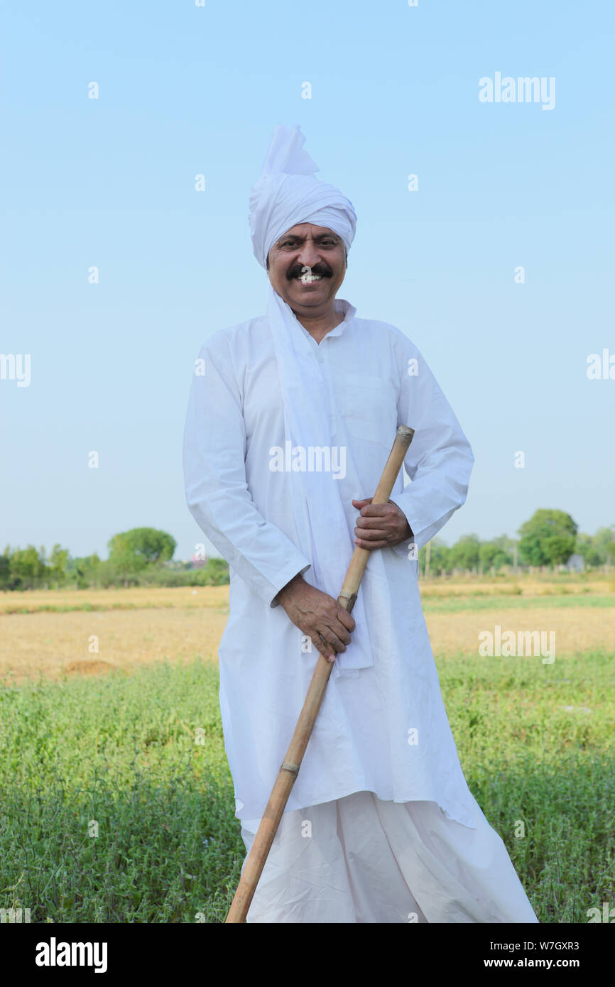 Rural man standing with cane in an agriculture field Stock Photo - Alamy