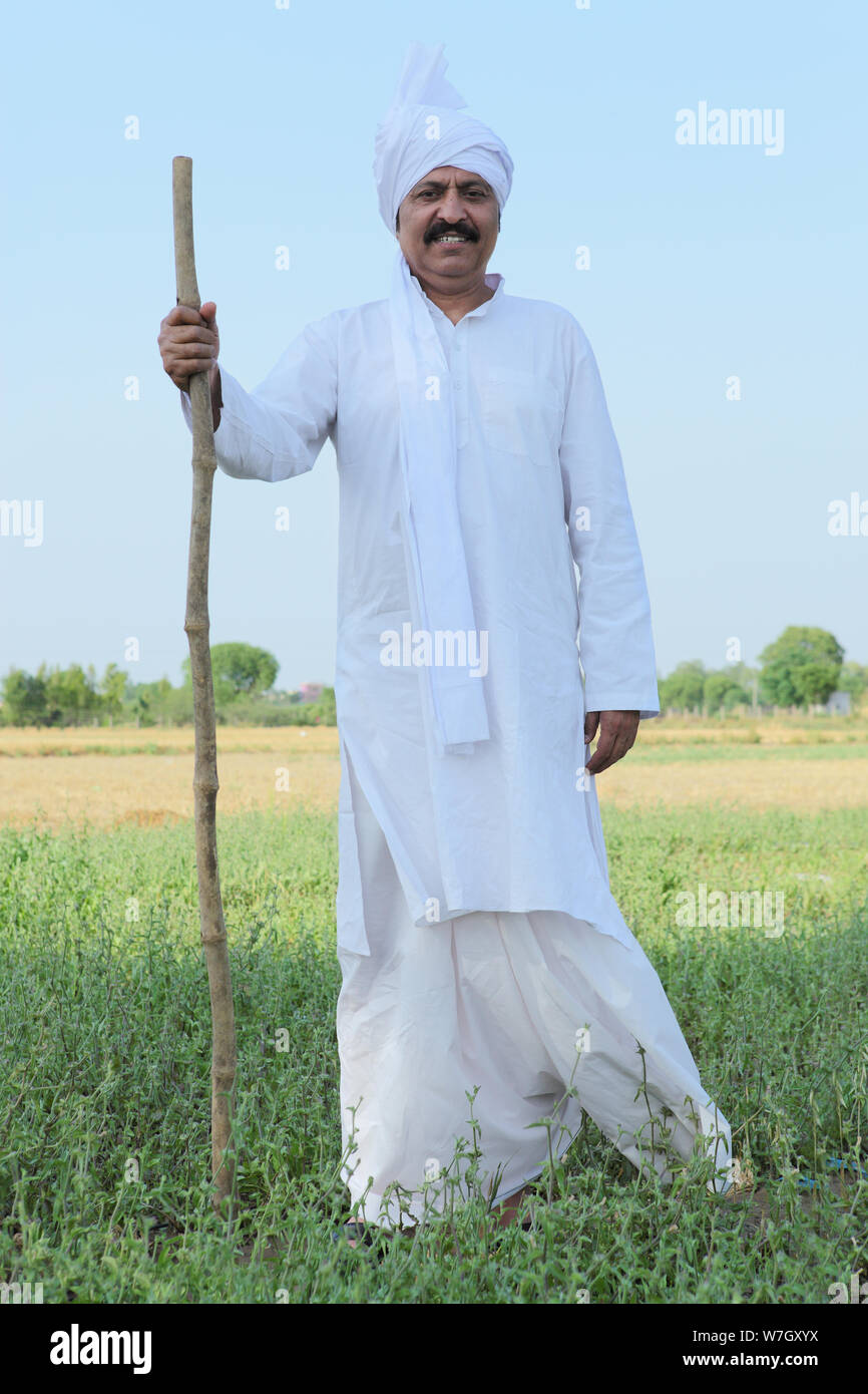 Rural man standing with cane in an agriculture field Stock Photo - Alamy