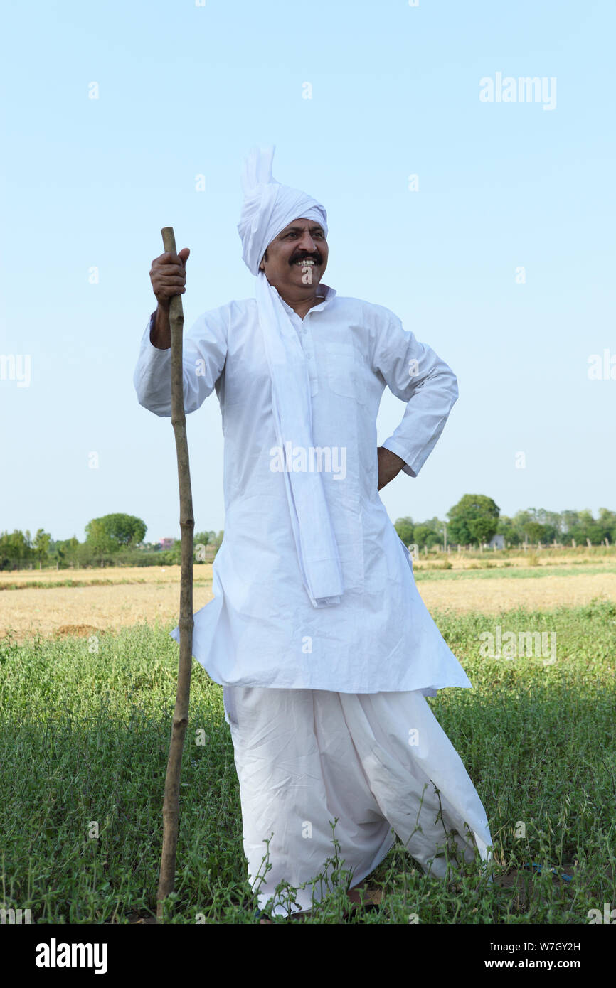 Rural man standing with cane in an agriculture field Stock Photo - Alamy