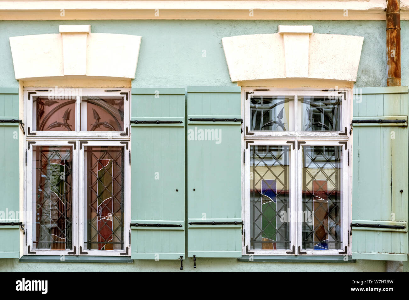 Two rectangular windows with white frames and green wooden shutters ...