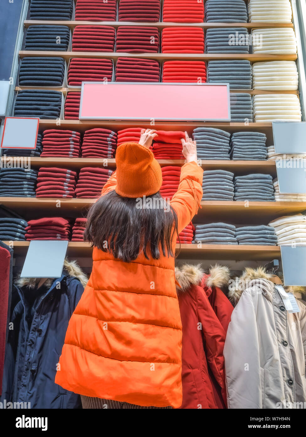 The girl holds out her hand for clothes on the store shelf. shopper ...
