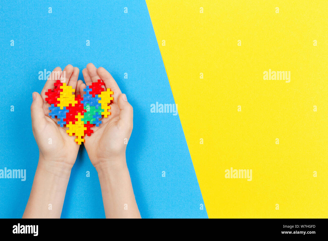 Kid hand holding colorful heart on yellow and blue background. World ...