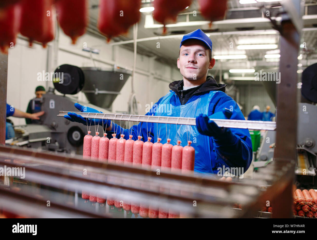 Portrait of butchers processing sausages at meat factory Stock Photo ...