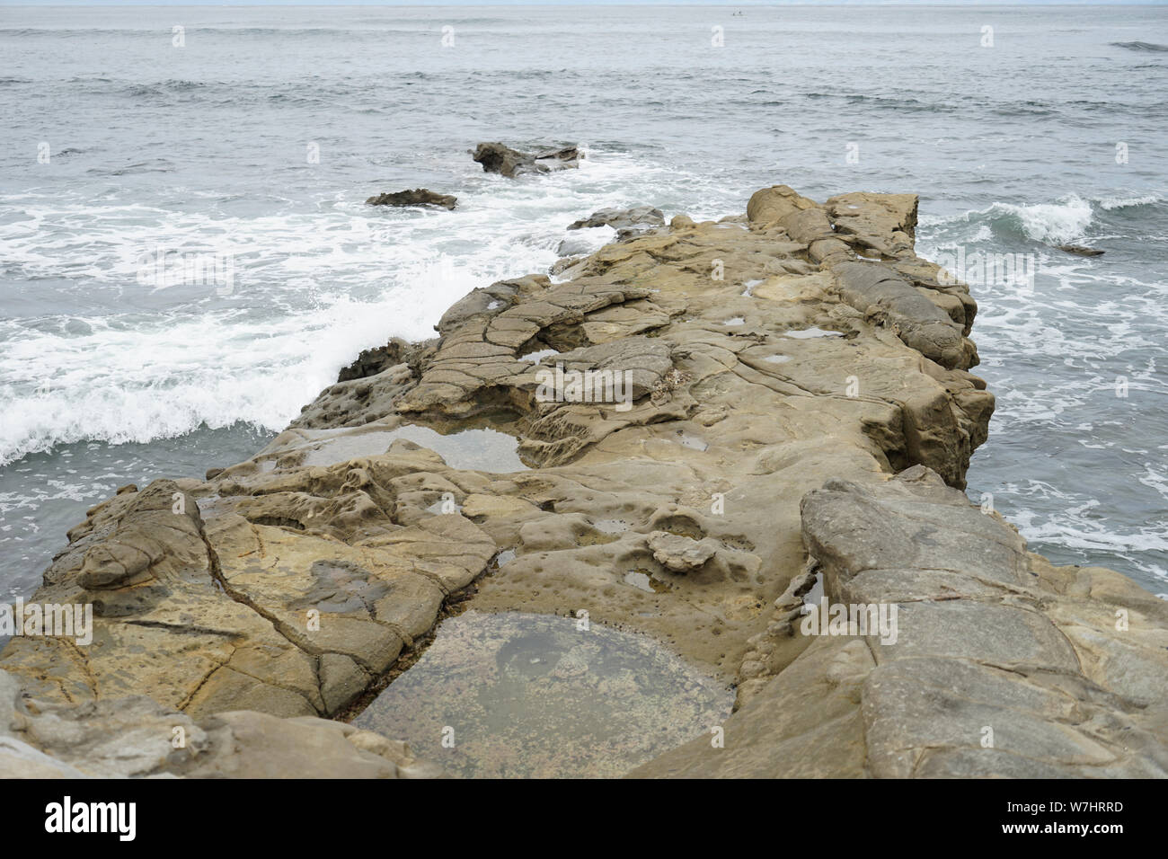 Rough water spills onto a rock ledge by a beach cove Stock Photo - Alamy