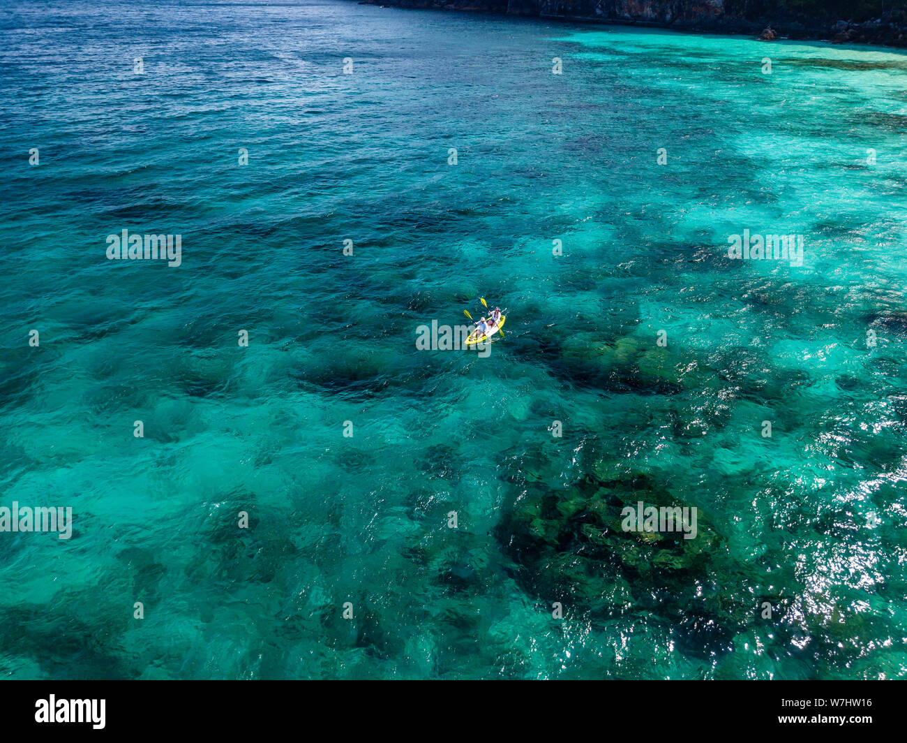 Aerial drone view of a sea kayak exploring a beautiful tropical coral ...