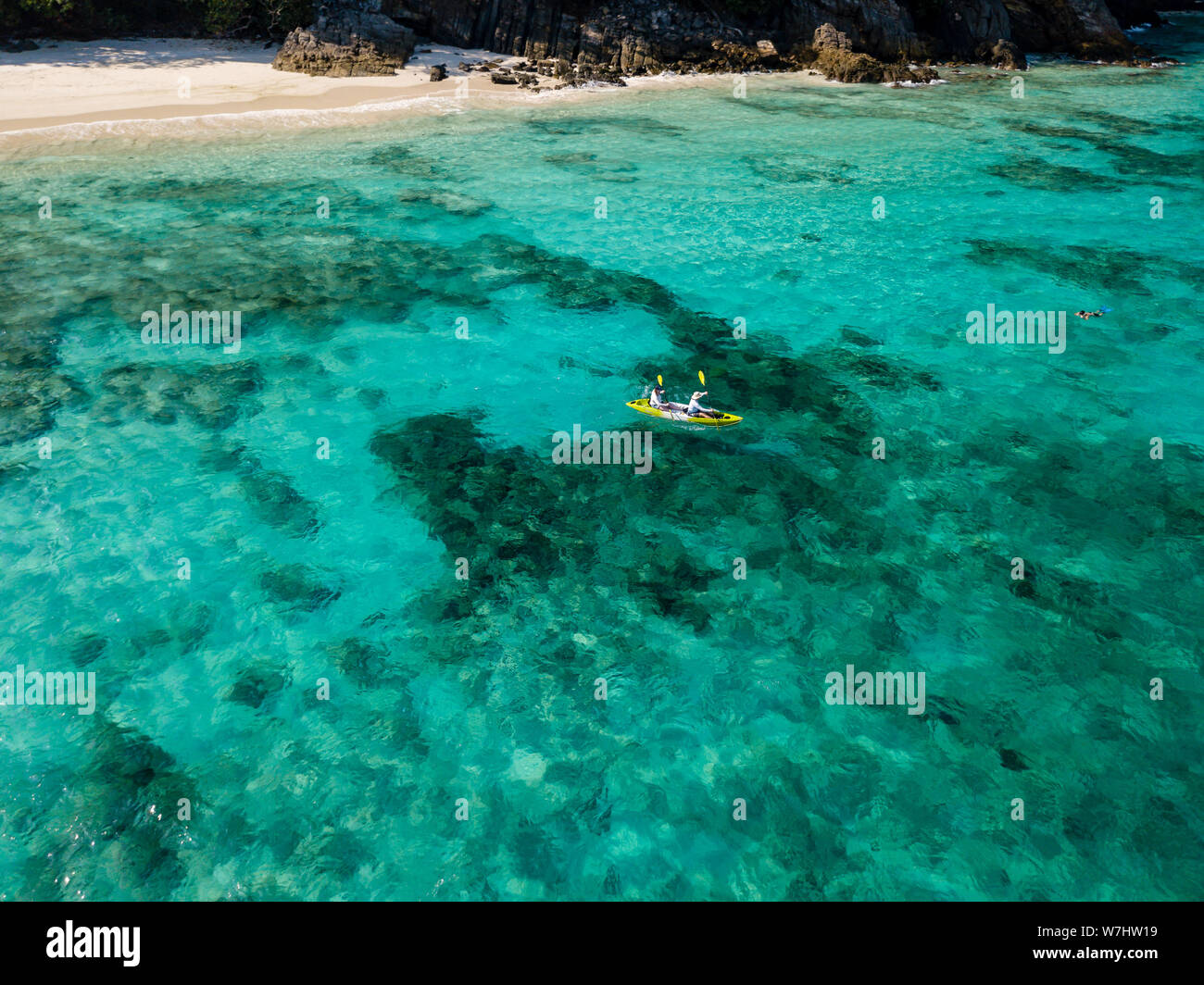 Aerial drone view of a sea kayak exploring a beautiful tropical coral ...