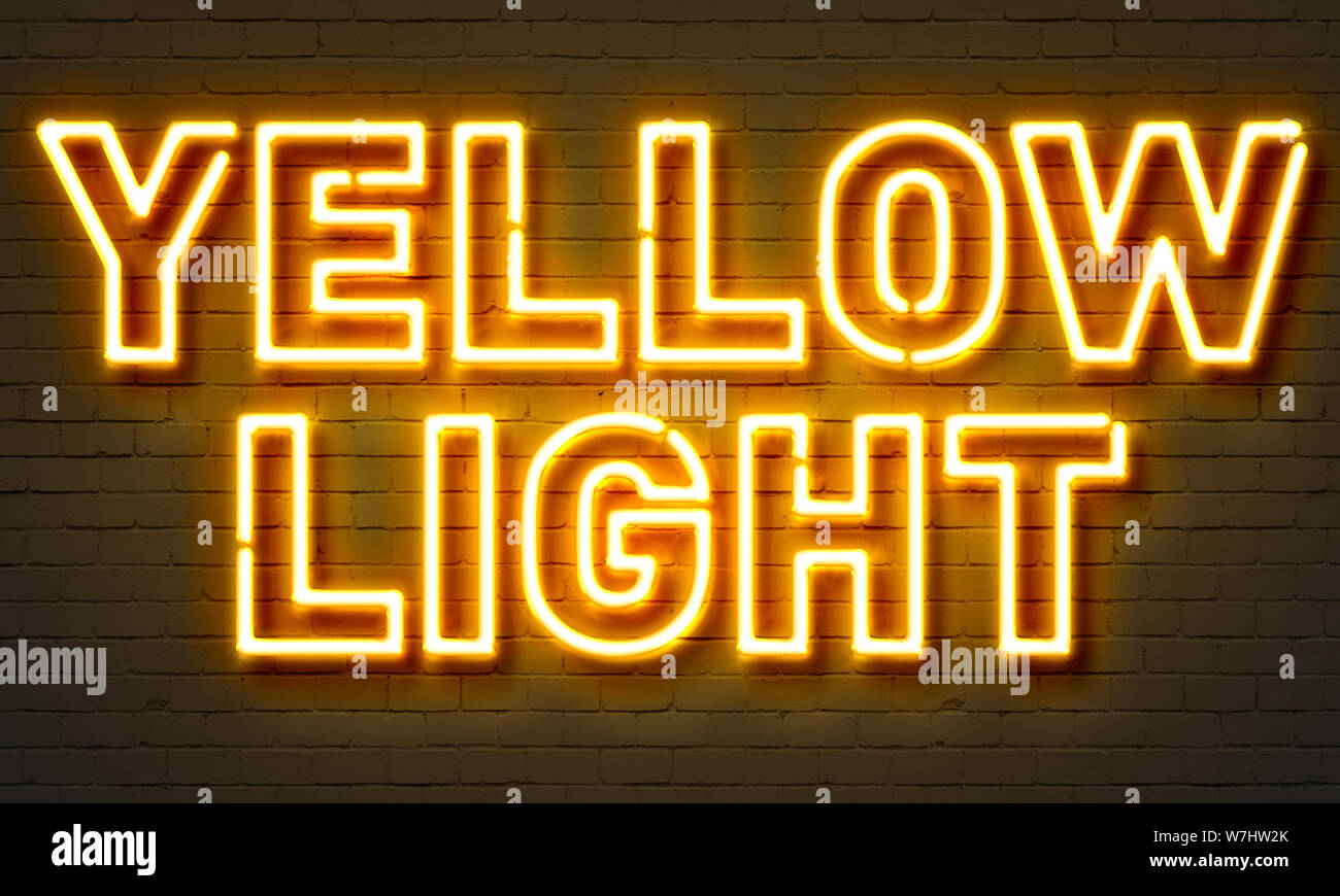 Yellow light neon sign on brick wall background Stock Photo - Alamy