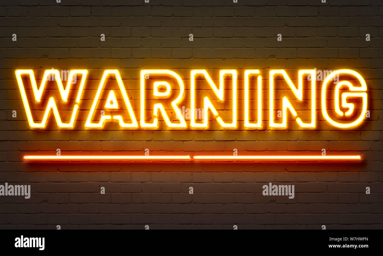 Warning neon sign on brick wall background Stock Photo - Alamy
