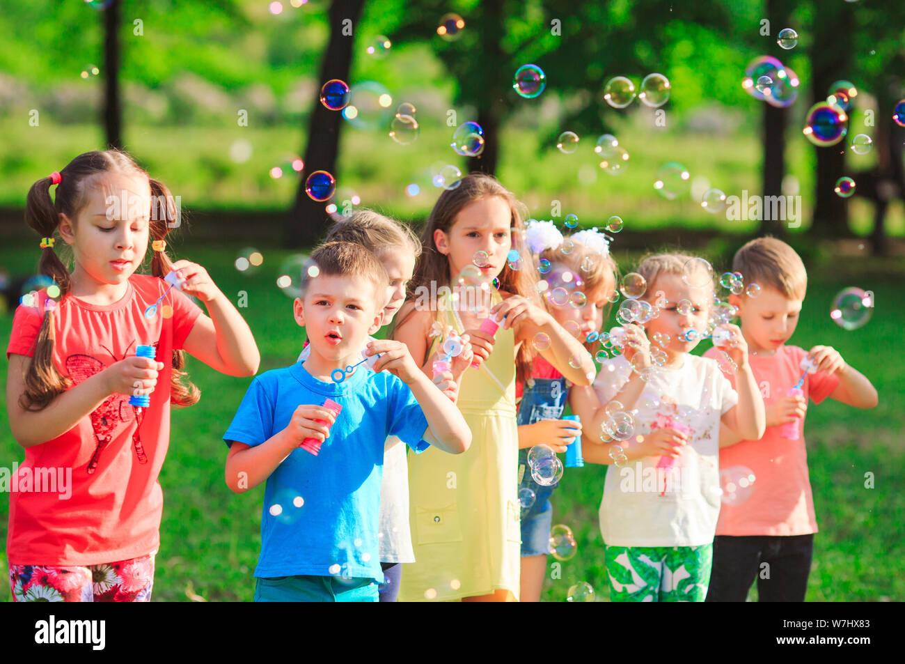 Group of children blowing soap bubbles in a garden Stock Photo - Alamy
