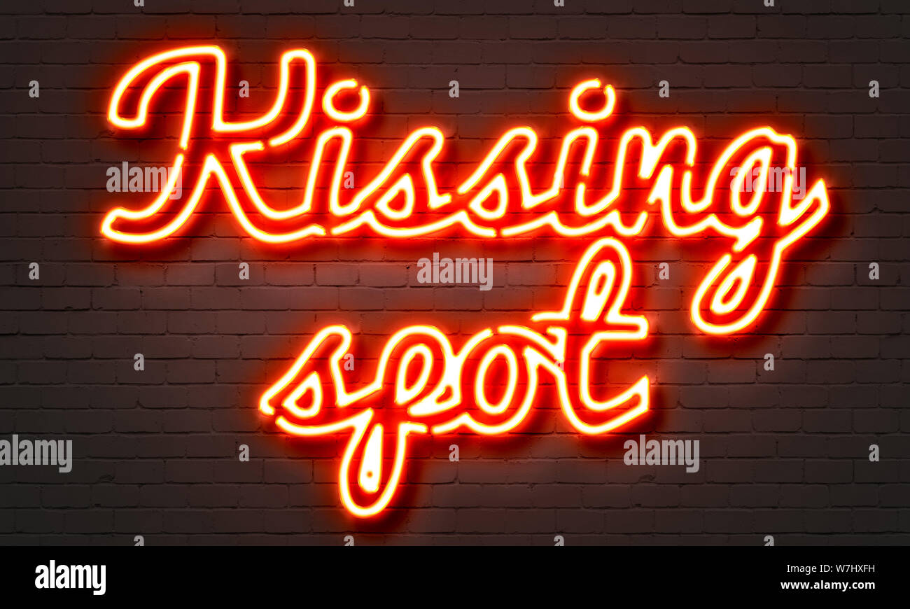Kissing spot neon sign on brick wall background Stock Photo - Alamy